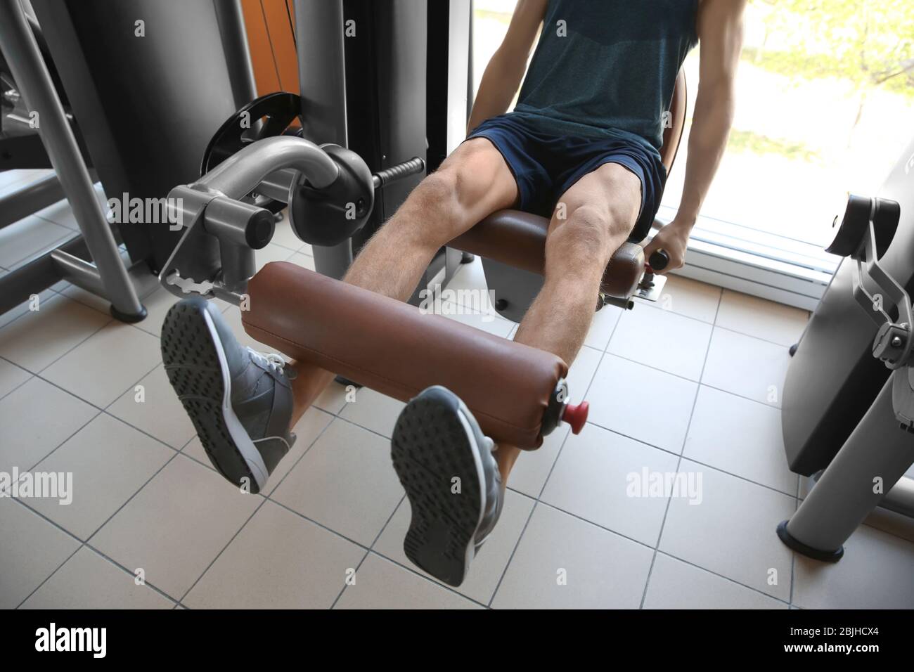 Sporty young man training legs in gym Stock Photo - Alamy