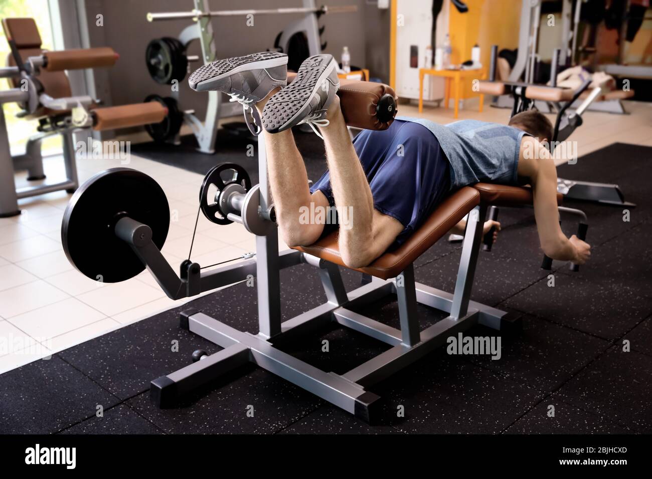 Sporty young man training legs in gym Stock Photo - Alamy