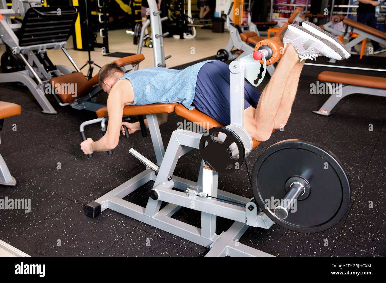 Sporty young man training legs in gym Stock Photo - Alamy