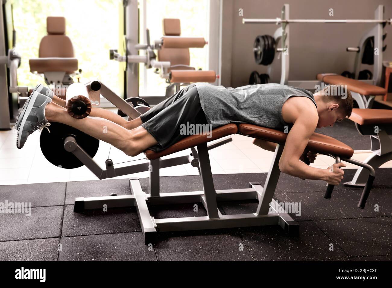 Sporty young man training legs in gym Stock Photo - Alamy