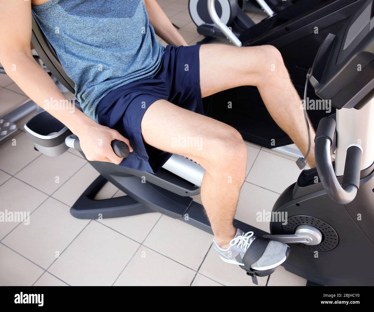 Sporty young man training legs in gym Stock Photo - Alamy