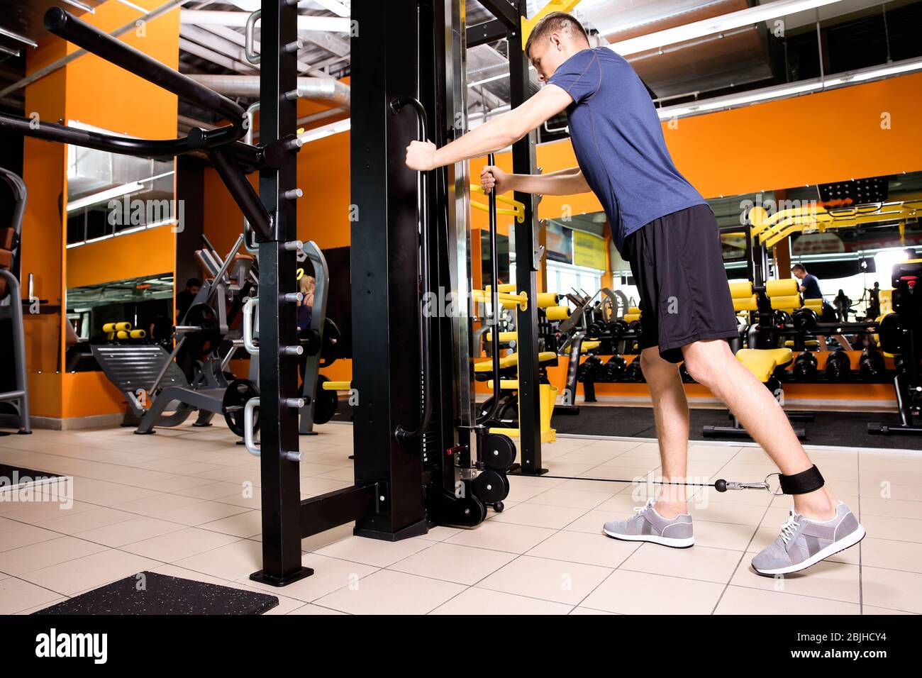 Sporty young man training legs in gym Stock Photo - Alamy