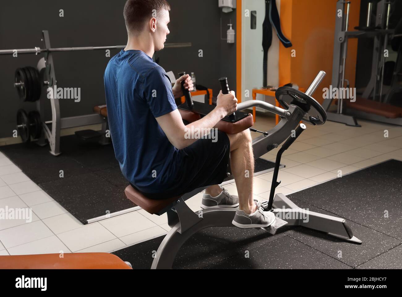 Sporty young man training legs in gym Stock Photo - Alamy