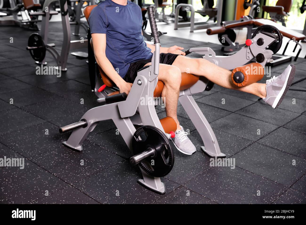 Sporty young man training legs in gym Stock Photo - Alamy