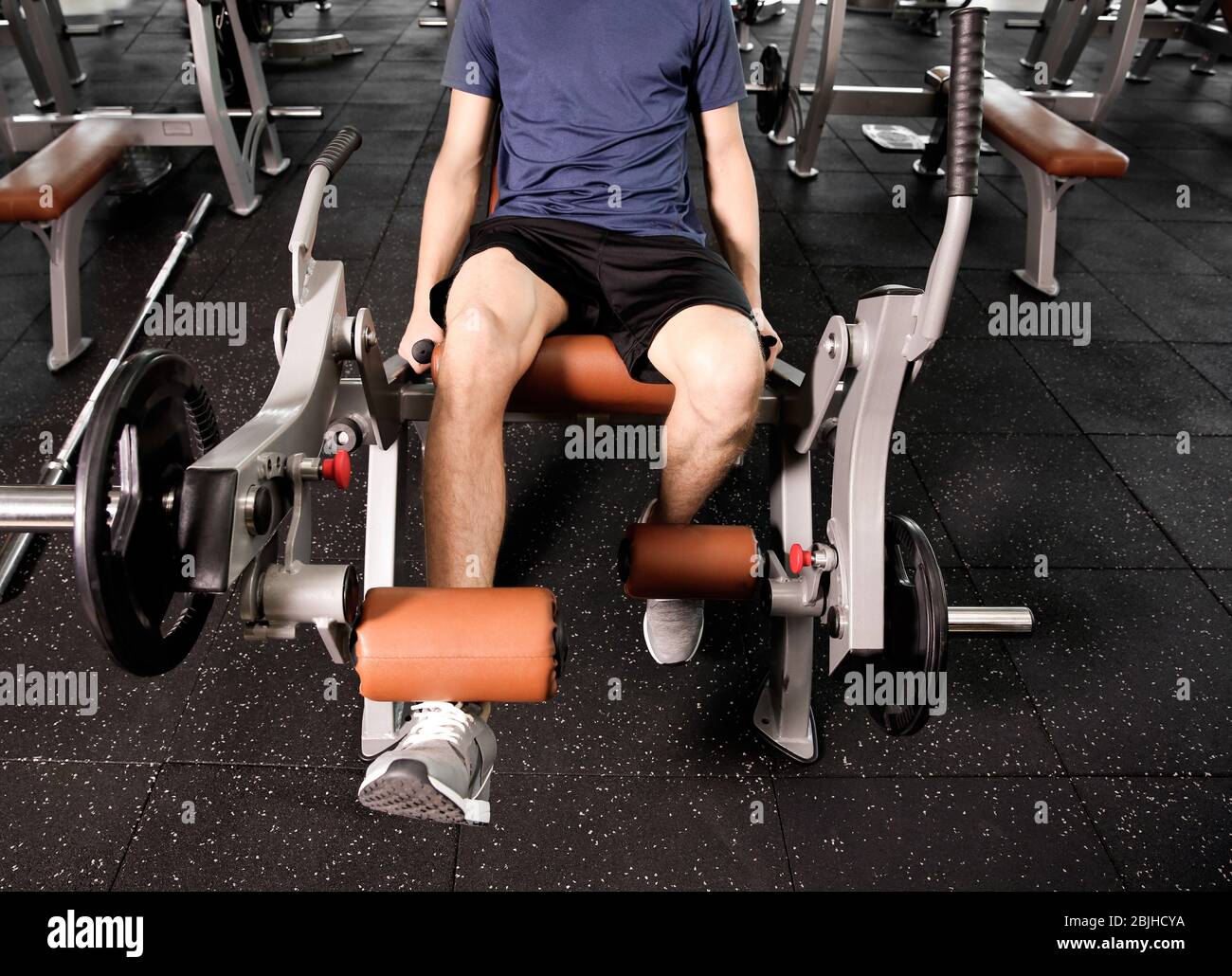 Sporty young man training legs in gym Stock Photo - Alamy