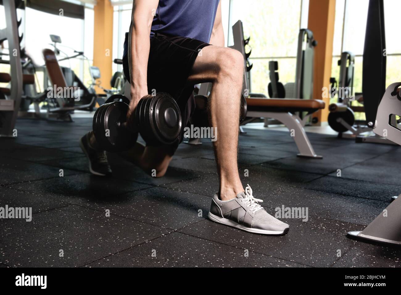 Sporty young man training legs in gym Stock Photo - Alamy