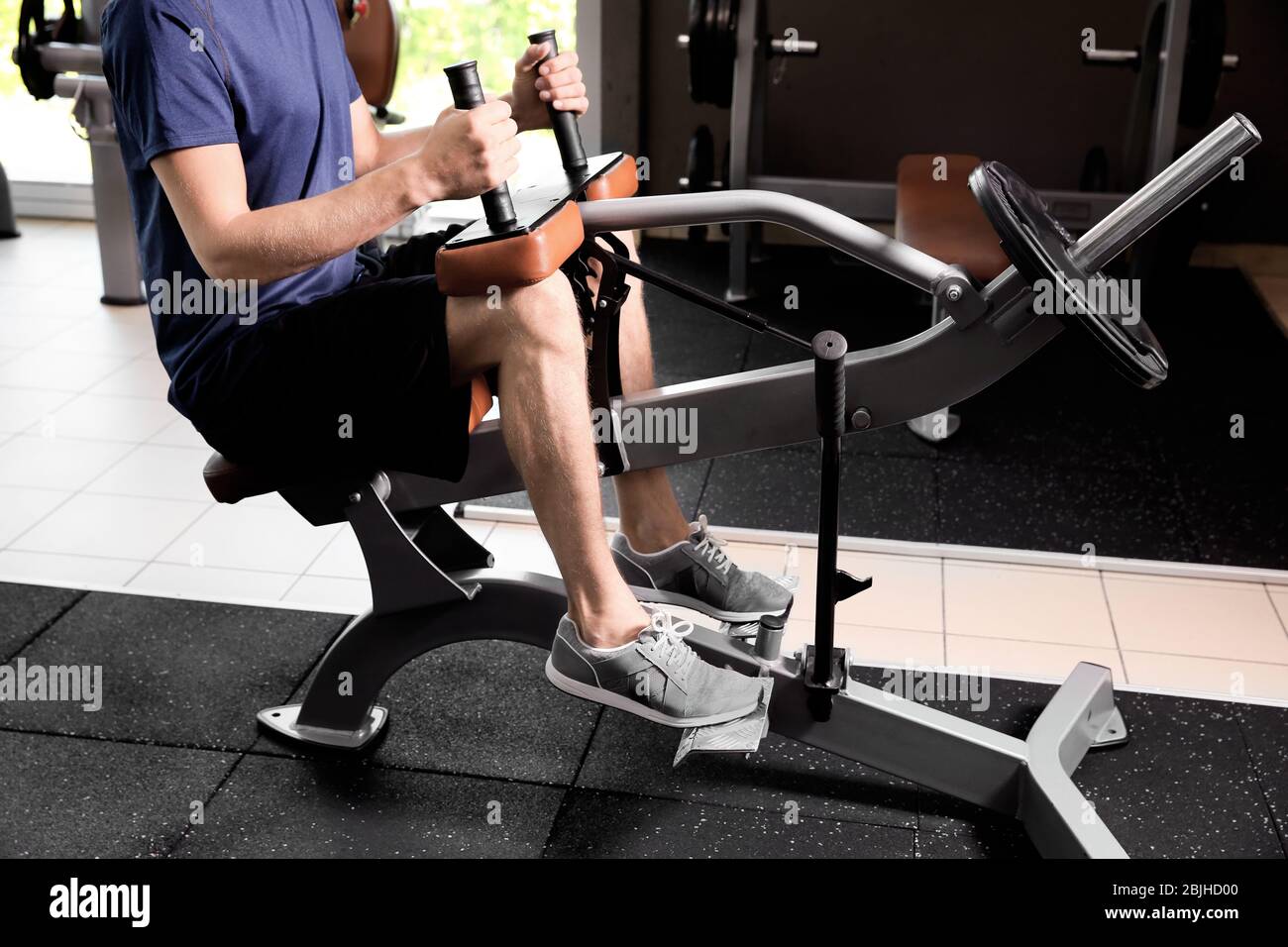 Sporty young man training legs in gym Stock Photo - Alamy