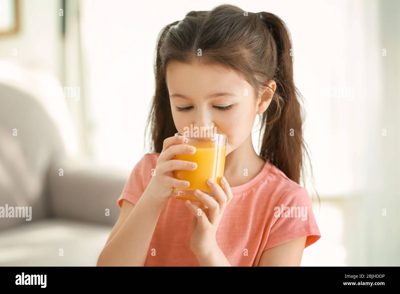 Cute little girl drinking juice at home Stock Photo - Alamy