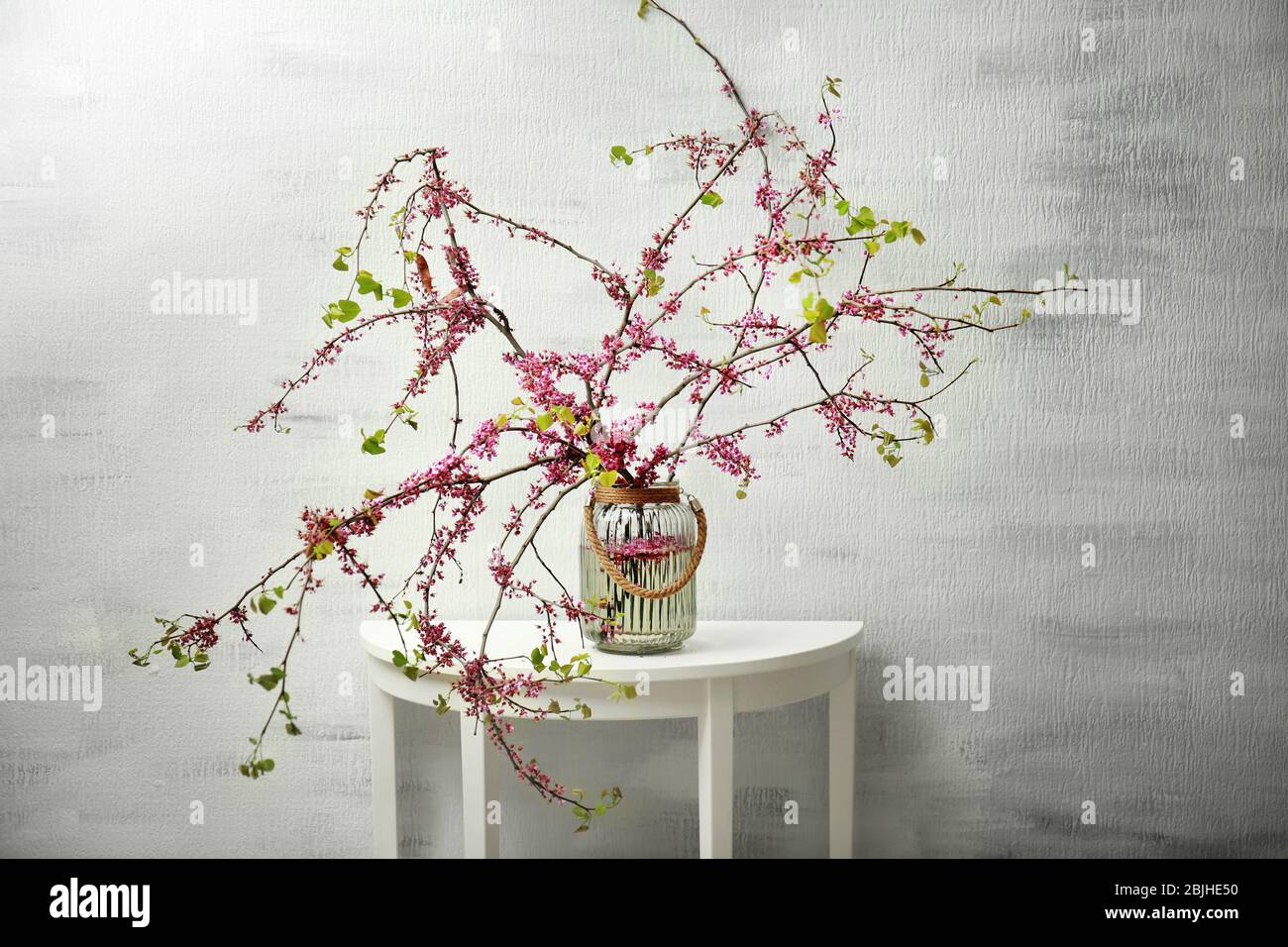 Glass vase with branches of blooming tree flowers on table Stock Photo ...