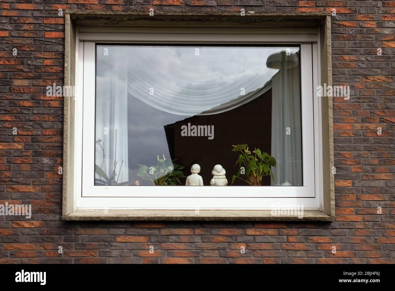 Outside view of beautiful window with statuettes and houseplants Stock ...