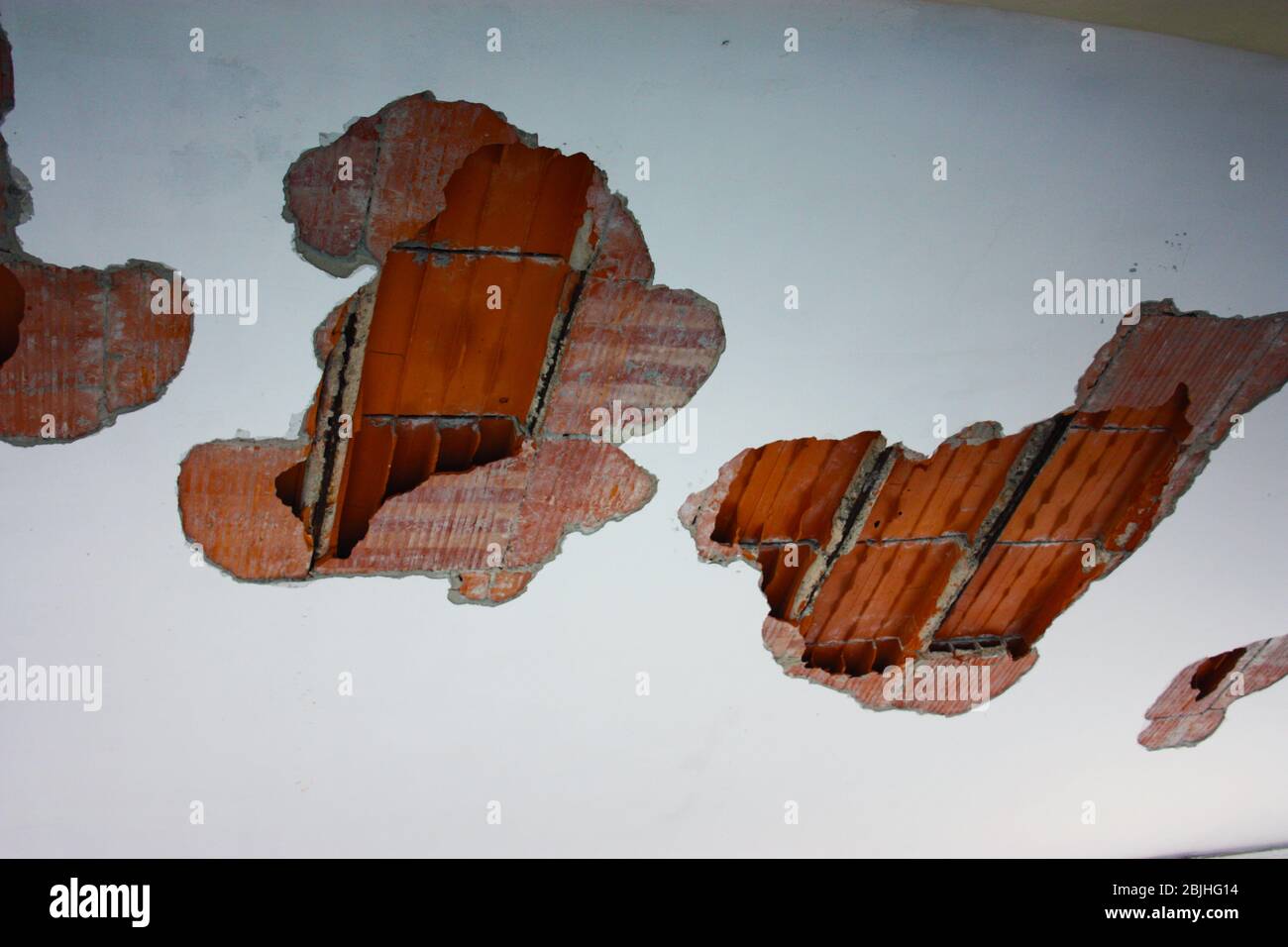 building hole in a crack on the white wall and red brick and concrete ...