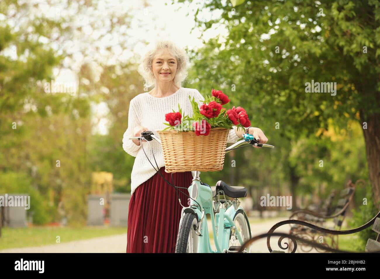 Beautiful middle aged woman with bicycle in park Stock Photo - Alamy