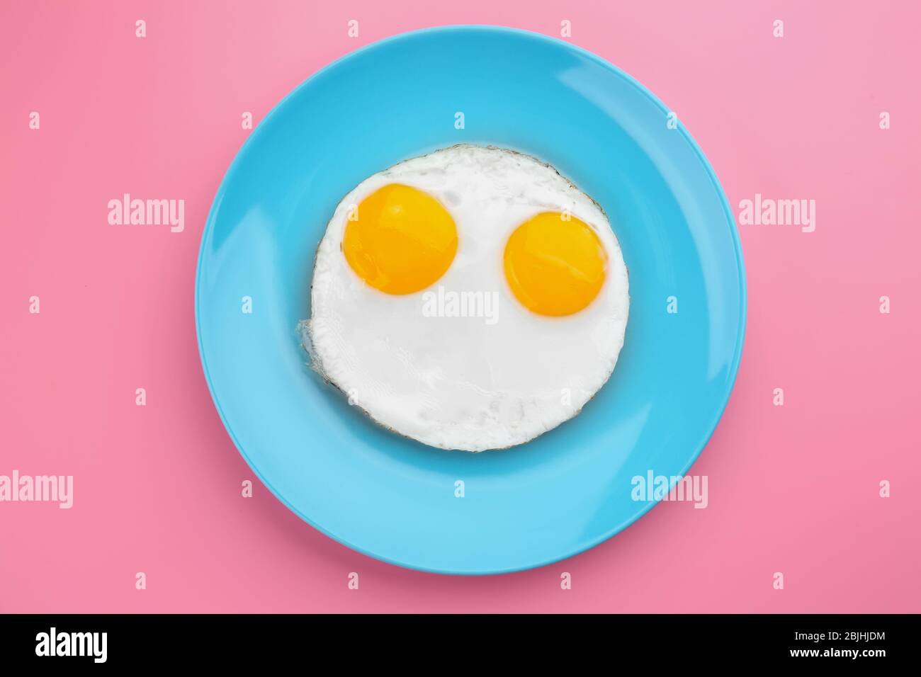 Plate with delicious sunny side up eggs on colour background Stock ...