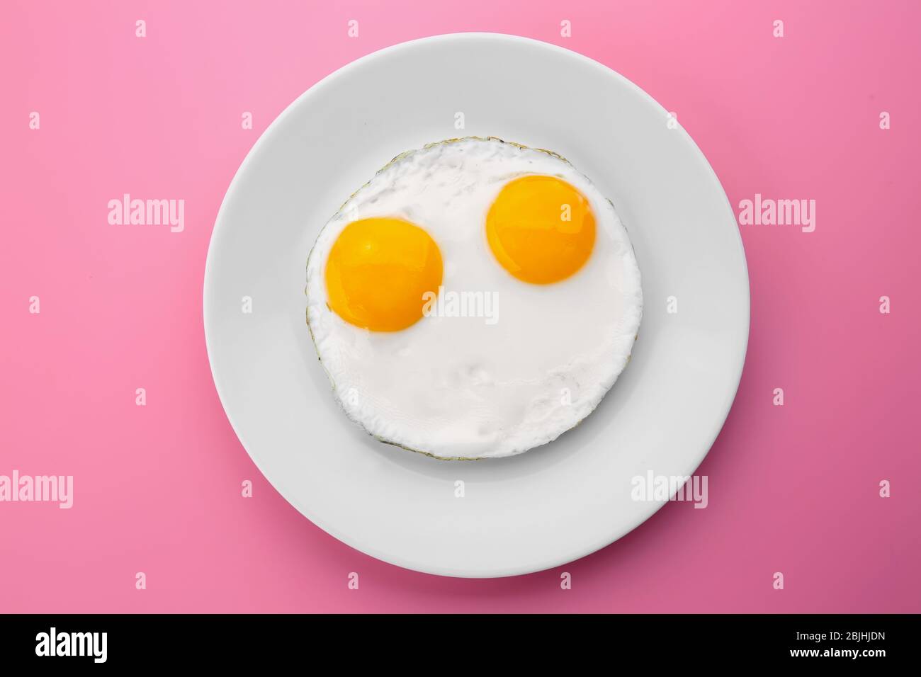 Plate with delicious sunny side up eggs on colour background Stock ...