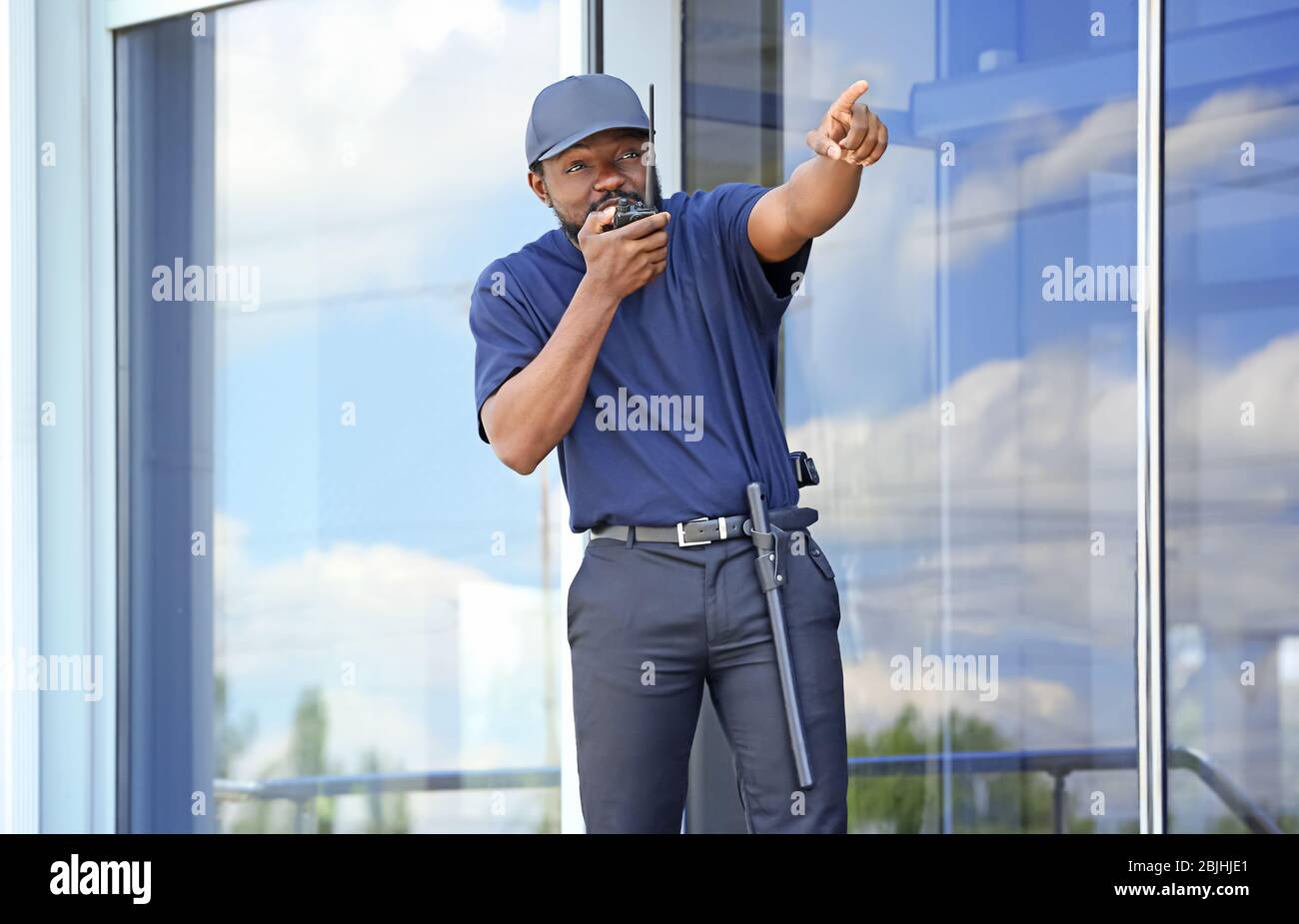 Male security guard using portable radio transmitter near big modern ...