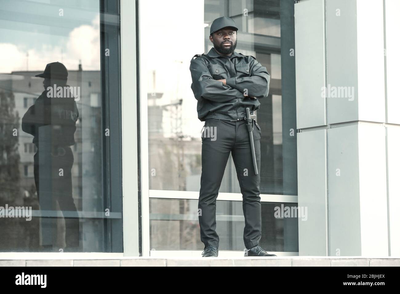 Male security guard standing near big modern building Stock Photo - Alamy