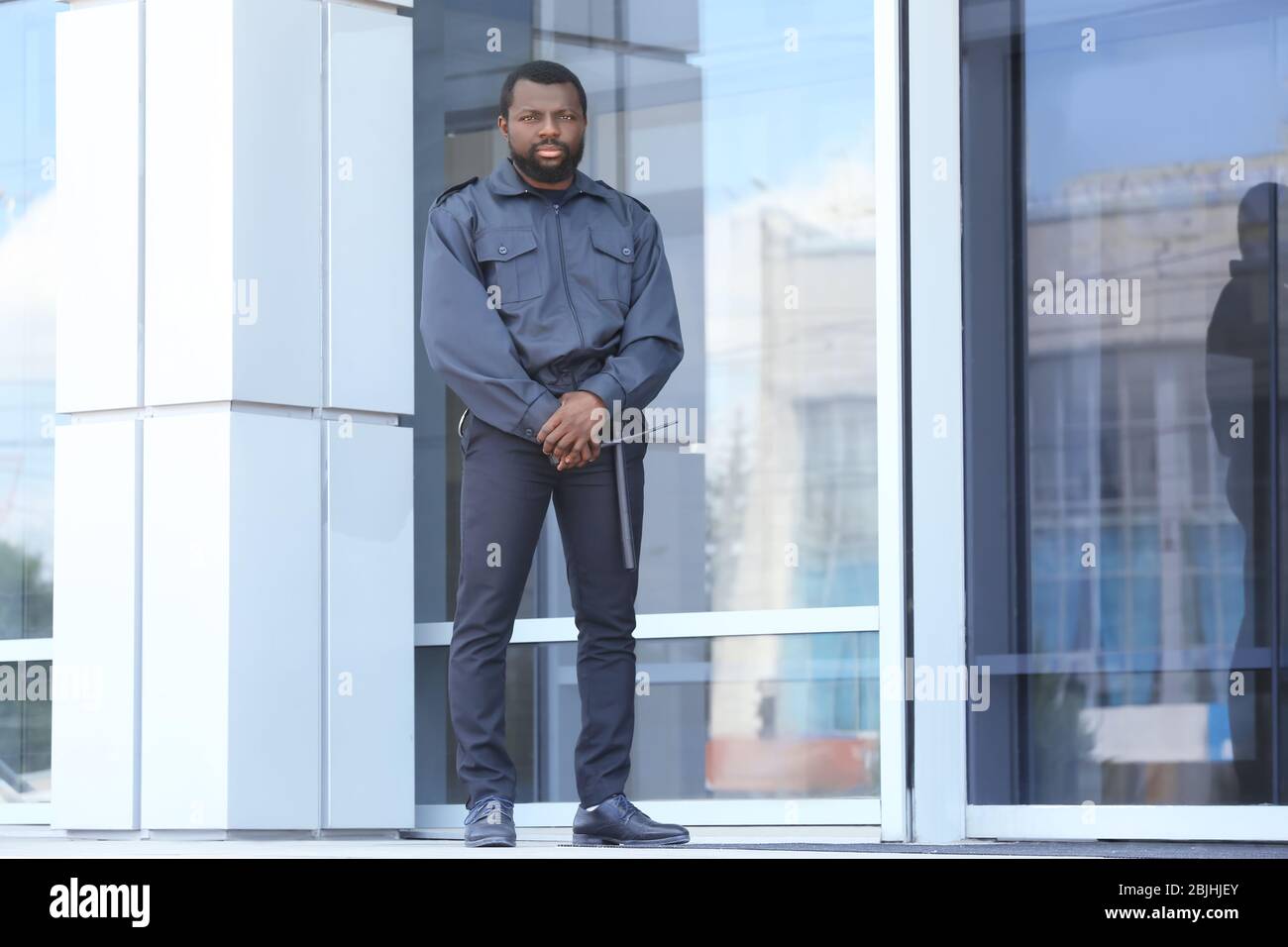 Male security guard near big modern building Stock Photo - Alamy