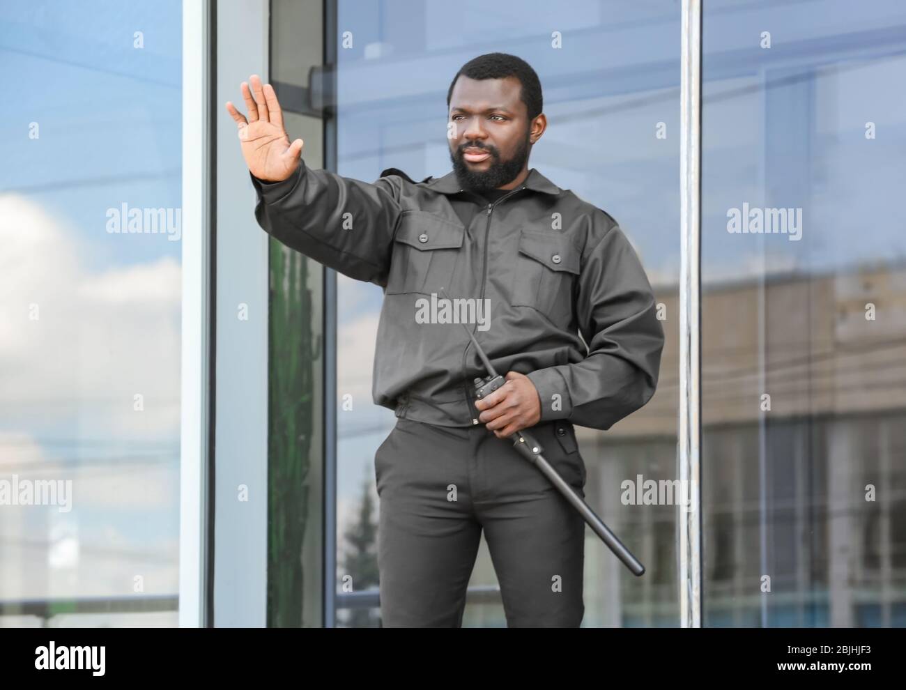 Male security guard showing stop gesture near big modern building Stock ...