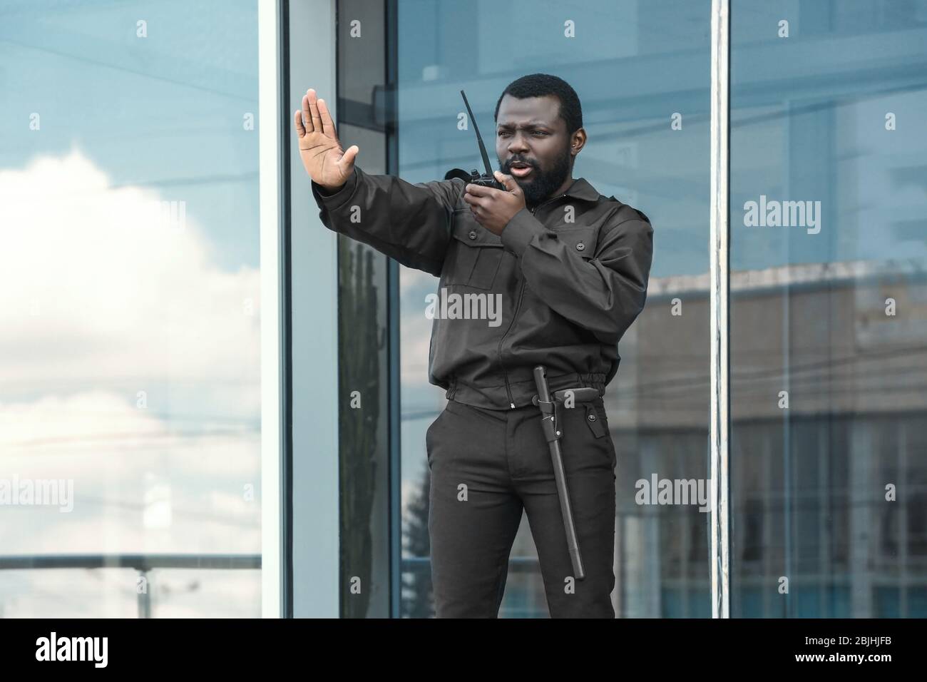 Male security guard showing stop gesture near big modern building Stock ...