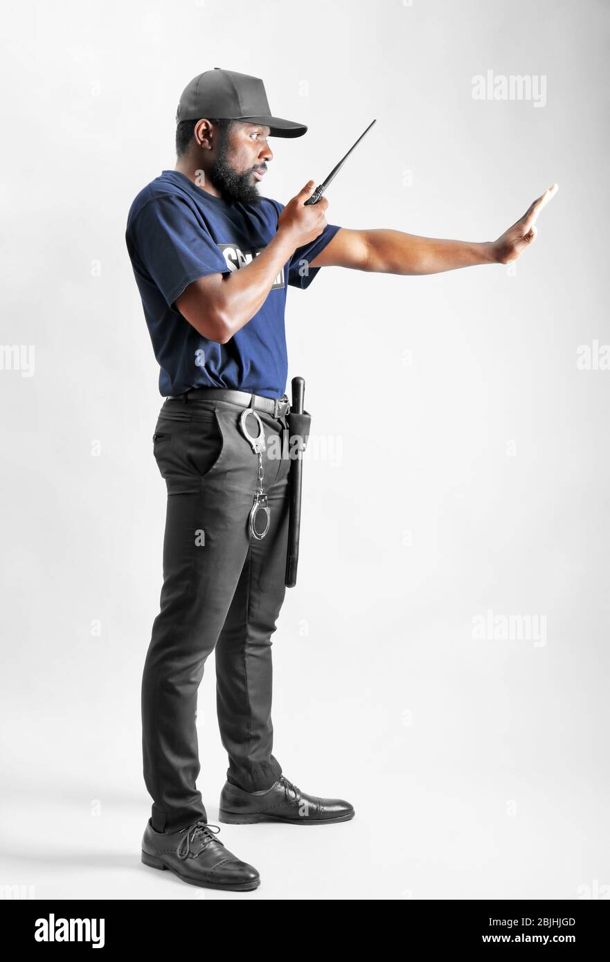 Male security guard showing stop gesture while using portable radio, on ...