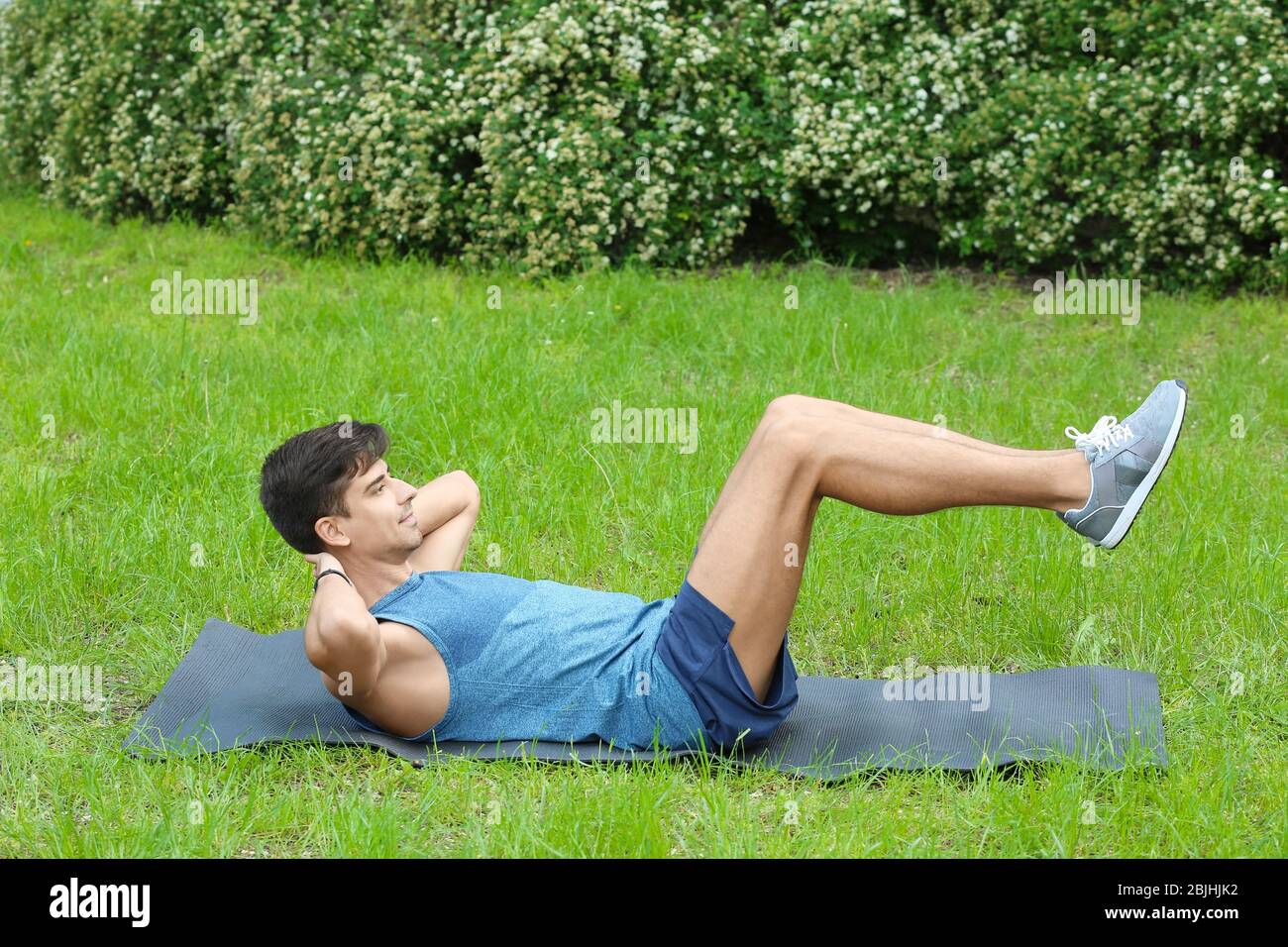 Athletic young man doing bicycle crunch exercise while lying on mat ...