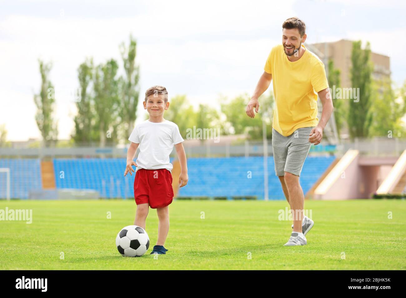 Dad and son playing football together in stadium Stock Photo - Alamy