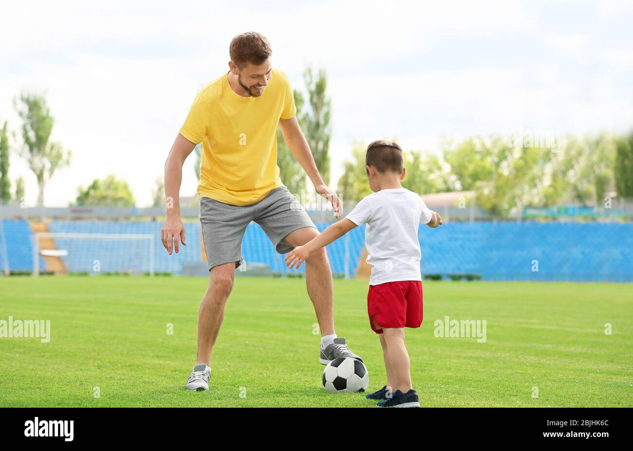 Dad and son playing football together in stadium Stock Photo - Alamy
