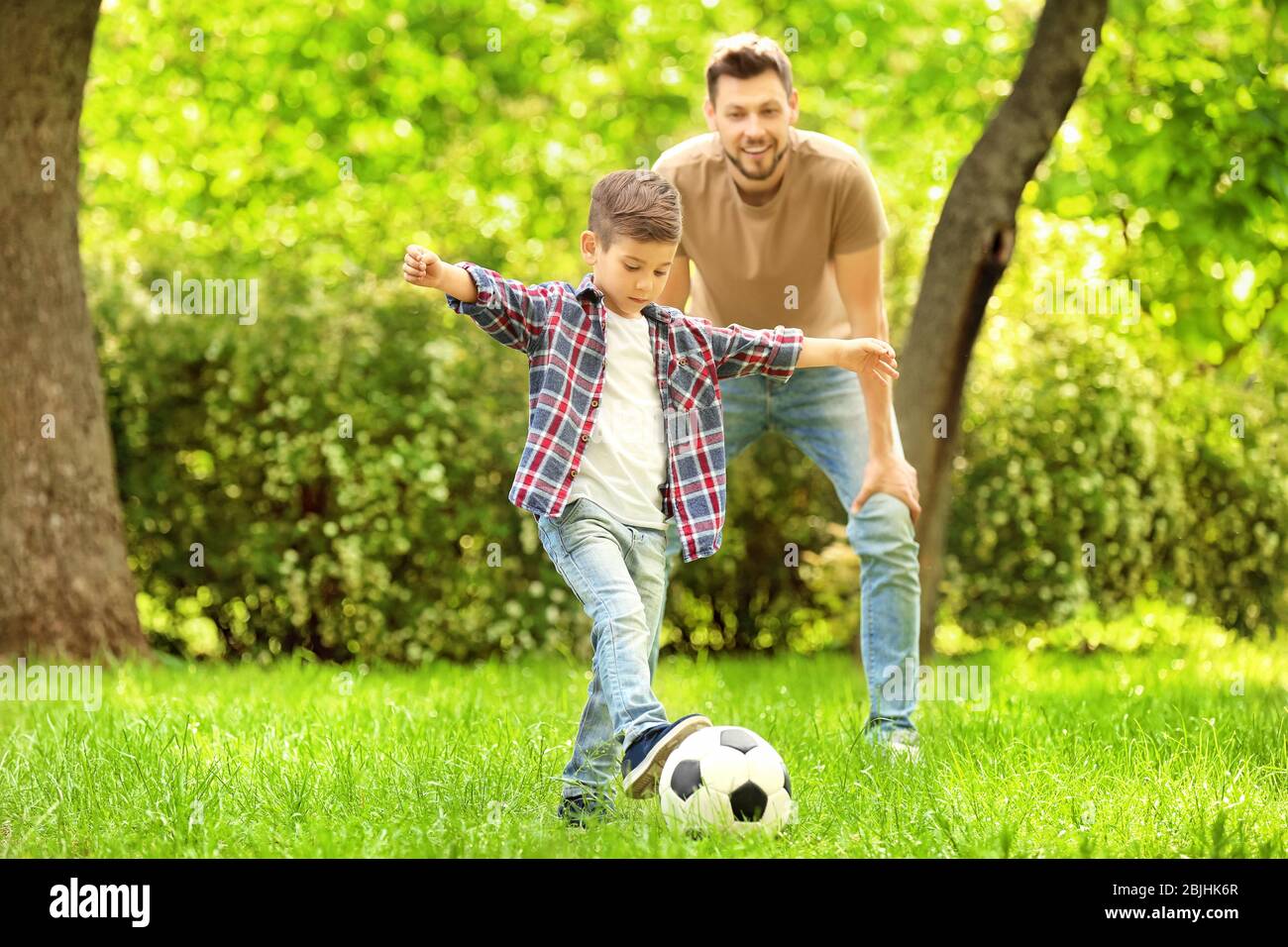 Dad and son playing football together on green meadow Stock Photo - Alamy