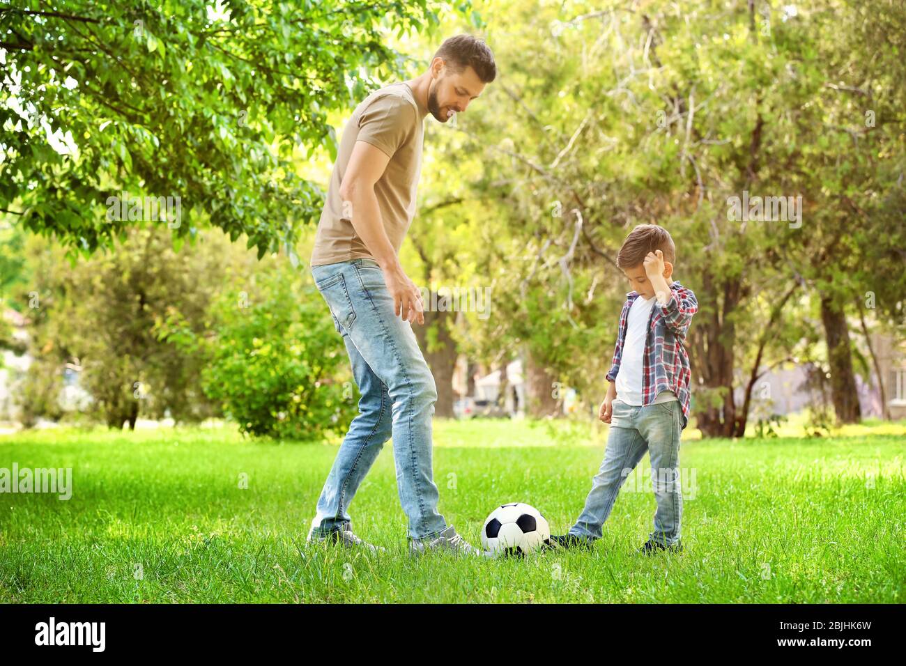 Dad and son playing football together on green meadow Stock Photo - Alamy