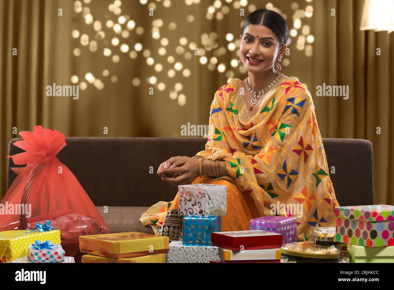 young woman sitting on a sofa with gift boxes Stock Photo - Alamy