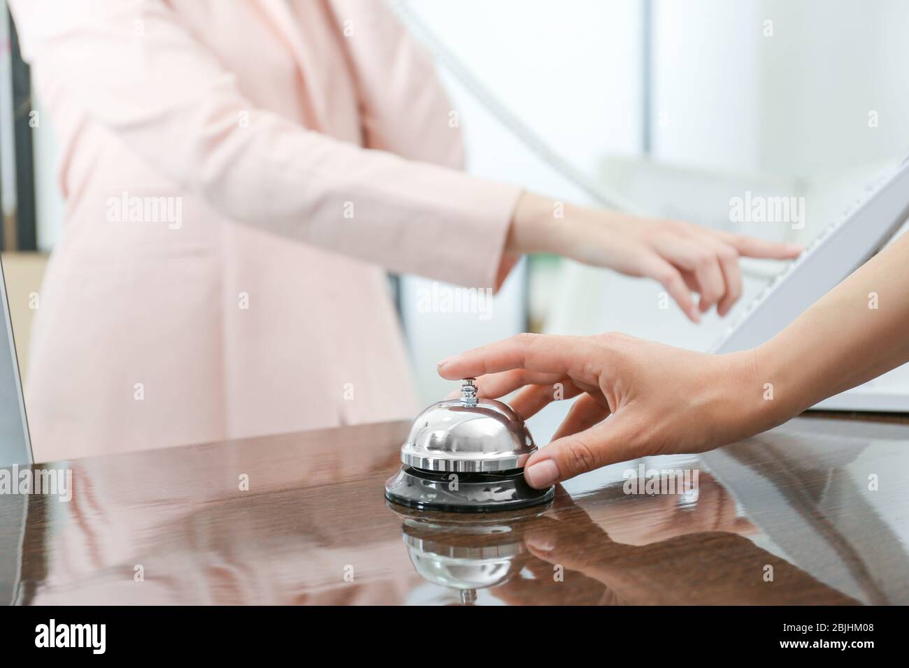 Woman ringing service bell in hotel lobby Stock Photo - Alamy
