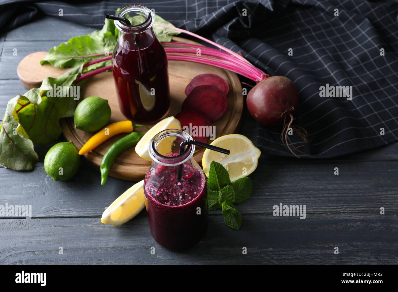 Composition with glass bottle of beet juice with straw on wooden table ...