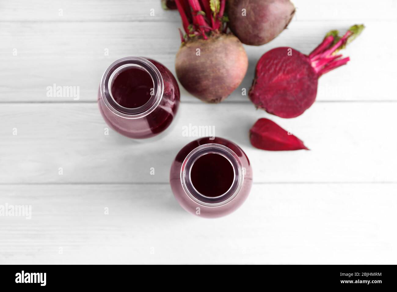 Two glass bottles with fresh smoothie and beets on wooden table Stock ...