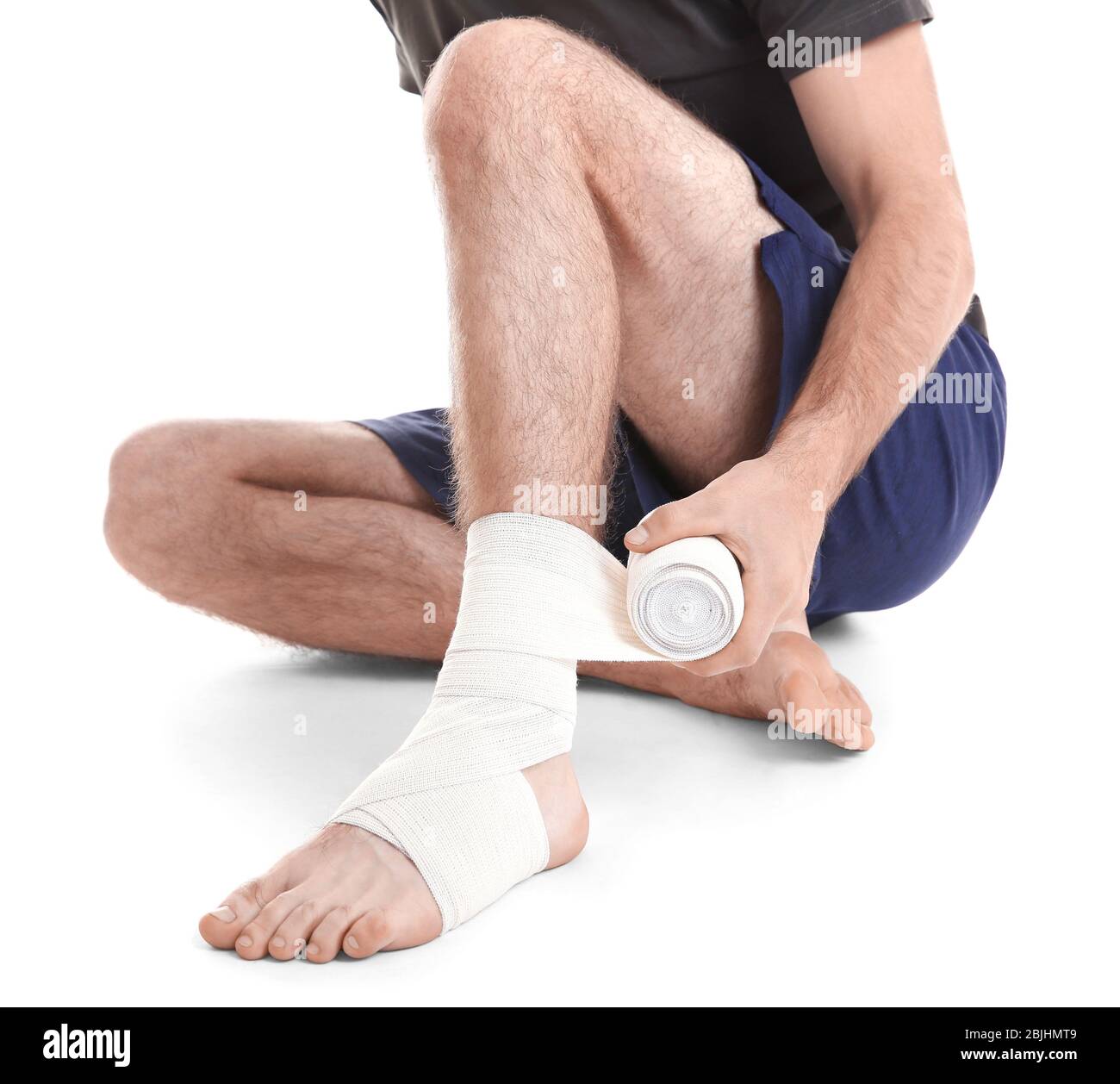 Young man applying bandage onto leg, on white background Stock Photo ...
