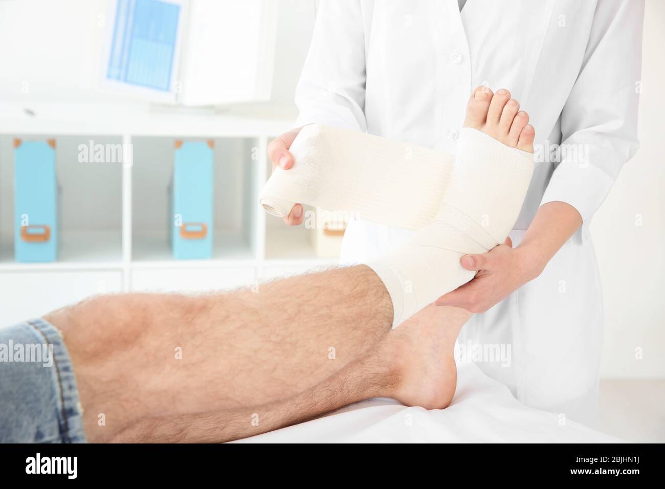 Doctor applying bandage onto patient's leg in clinic Stock Photo - Alamy