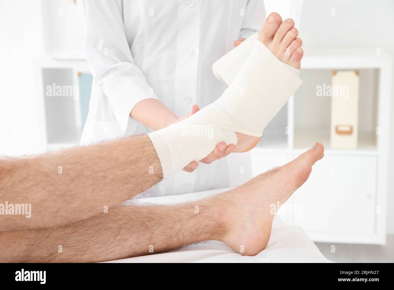 Doctor applying bandage onto patient's leg in clinic Stock Photo - Alamy