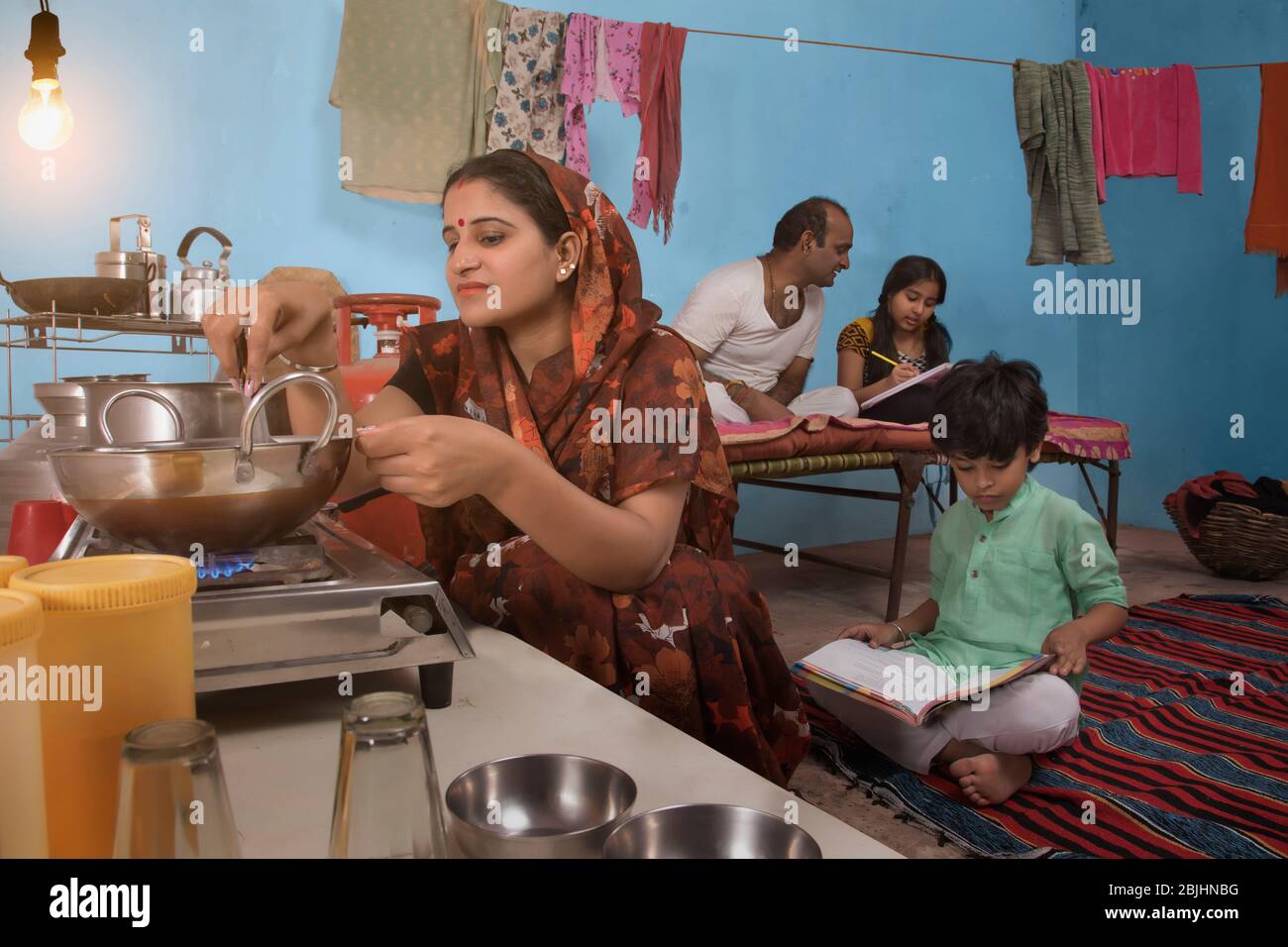 Childs studying in the kitchen while his mother is cooking Stock Photo ...