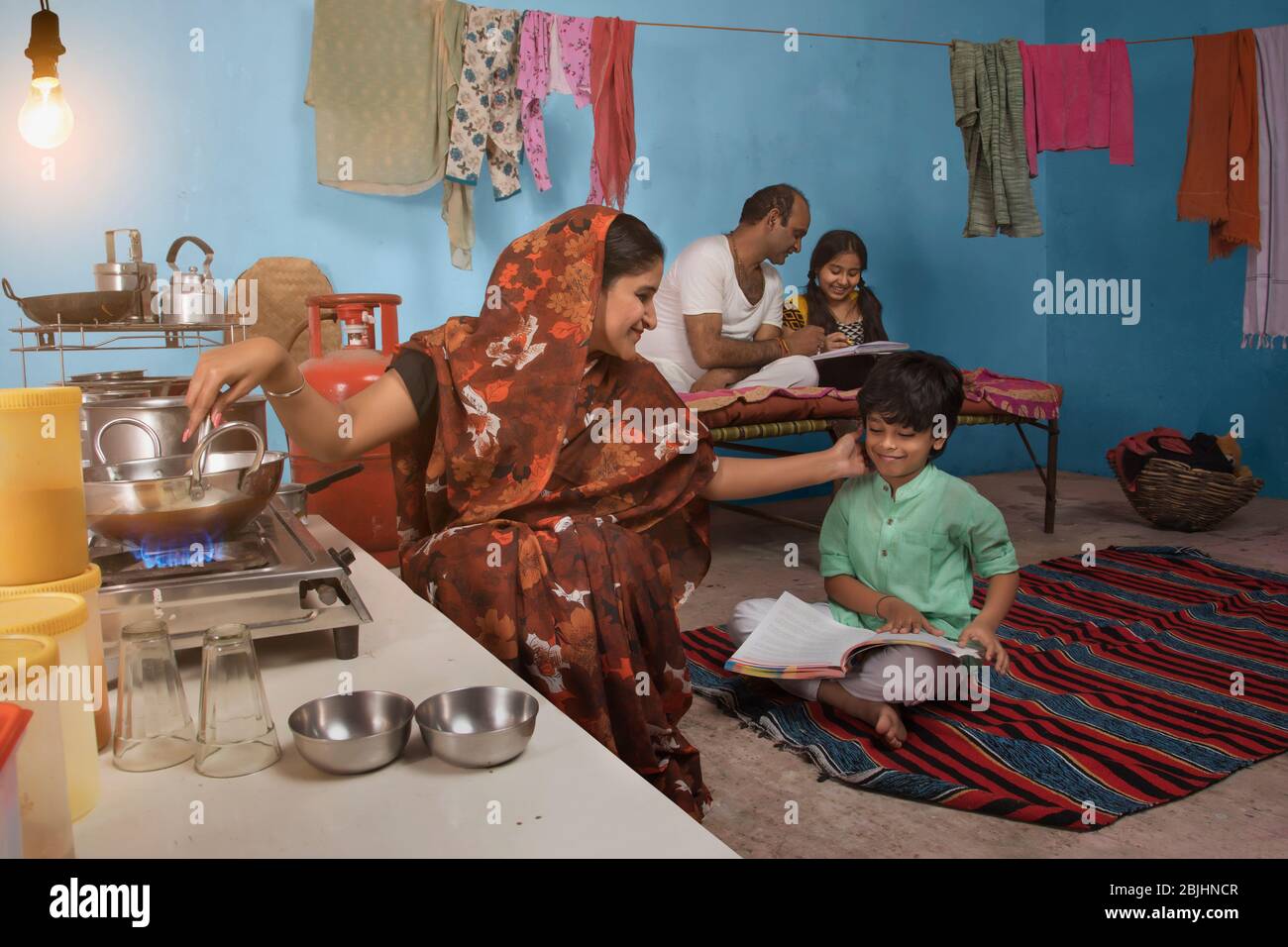 Childs studying in the kitchen while his mother is cooking Stock Photo ...