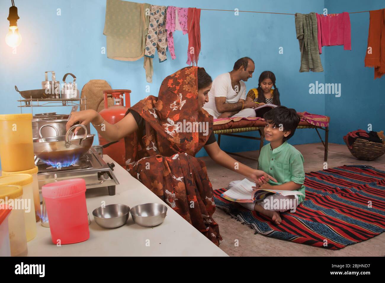 Childs studying in the kitchen while his mother is cooking Stock Photo ...