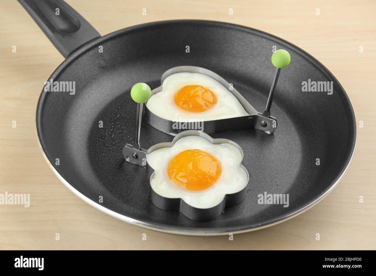 Frying pan with tasty over easy eggs in molds Stock Photo - Alamy
