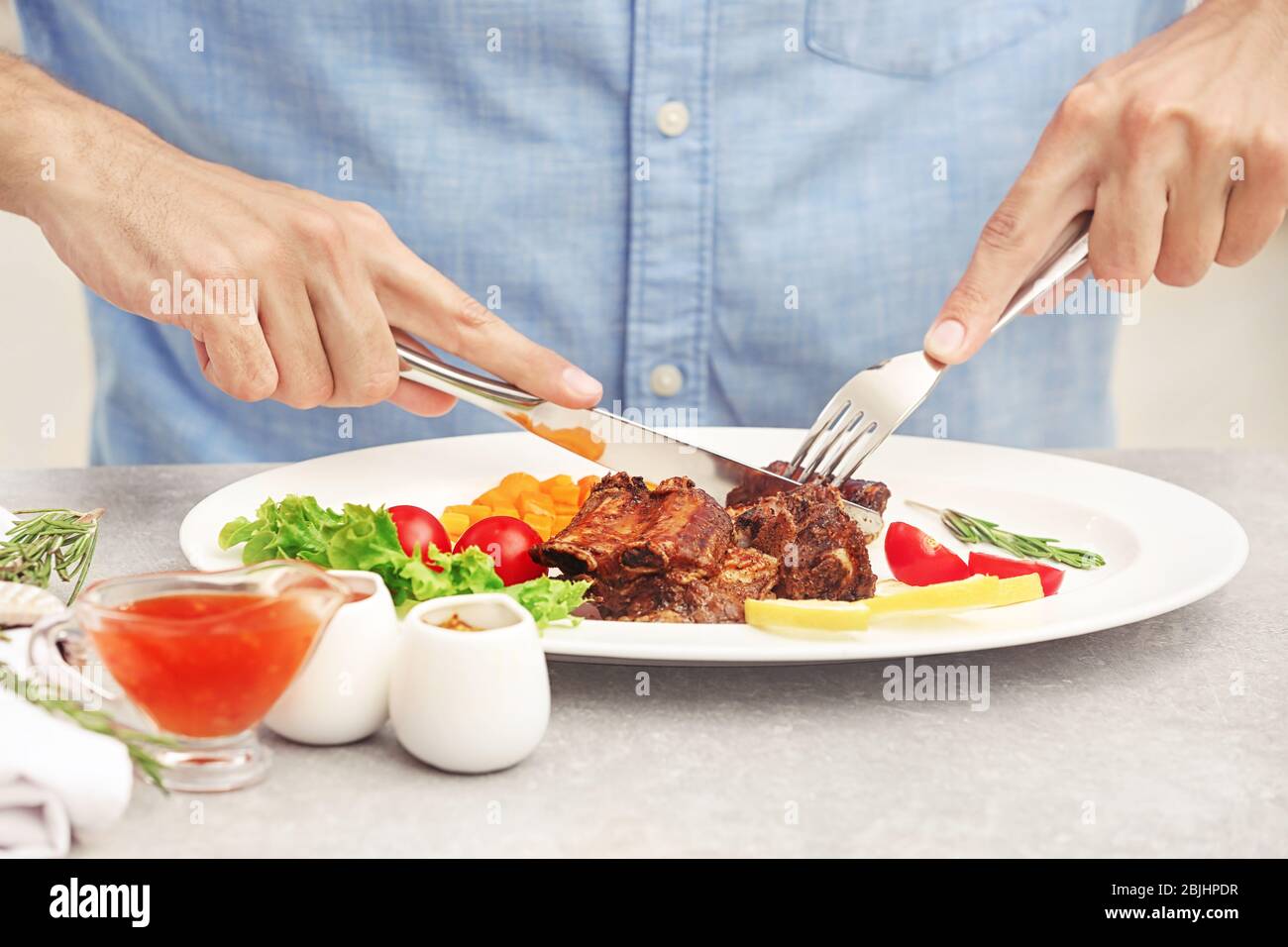 Young man eating delicious ribs in restaurant Stock Photo - Alamy