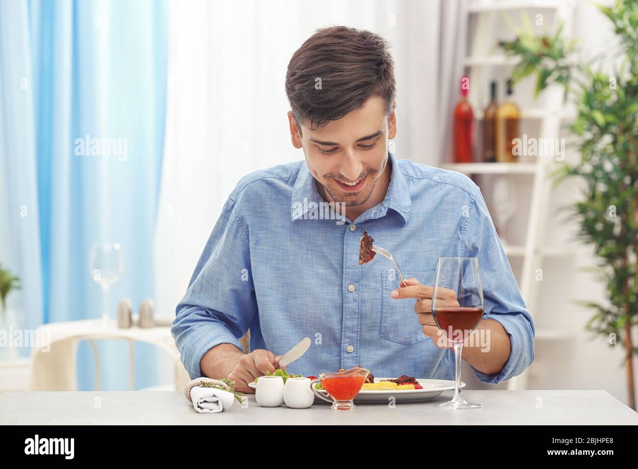 Young man eating delicious roasted ribs in restaurant Stock Photo - Alamy