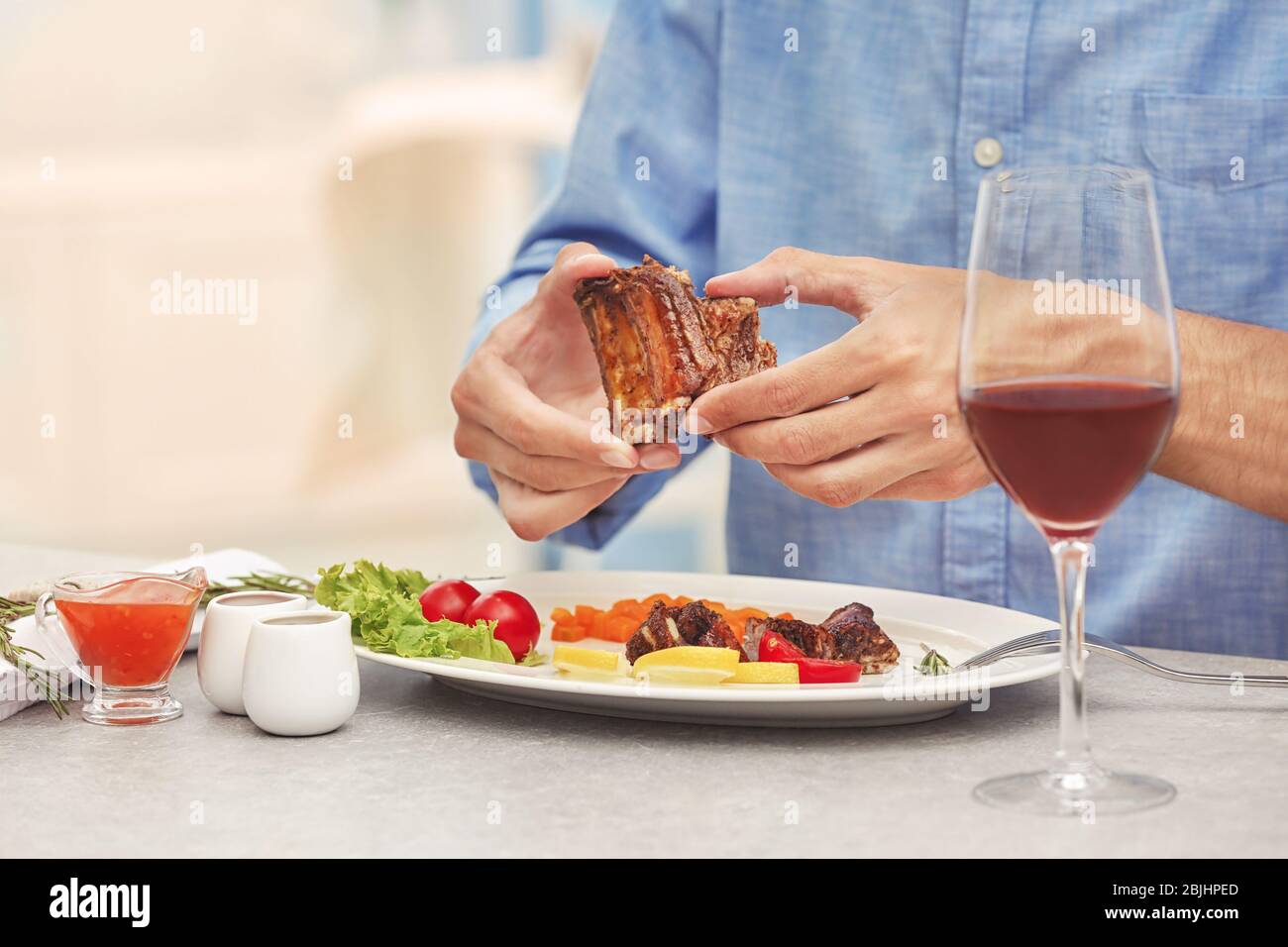 Young man eating delicious ribs in restaurant Stock Photo - Alamy