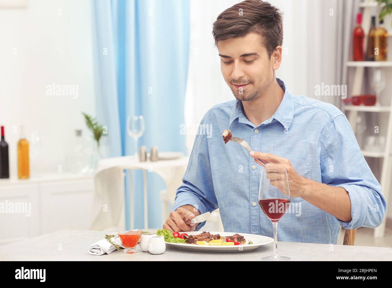 Young man eating delicious ribs in restaurant Stock Photo - Alamy
