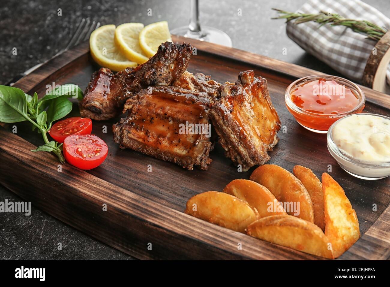 Wooden tray with delicious ribs and vegetables, closeup Stock Photo - Alamy
