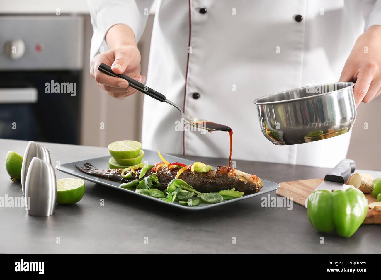 Chef pouring fish with delicious sauce in restaurant Stock Photo - Alamy