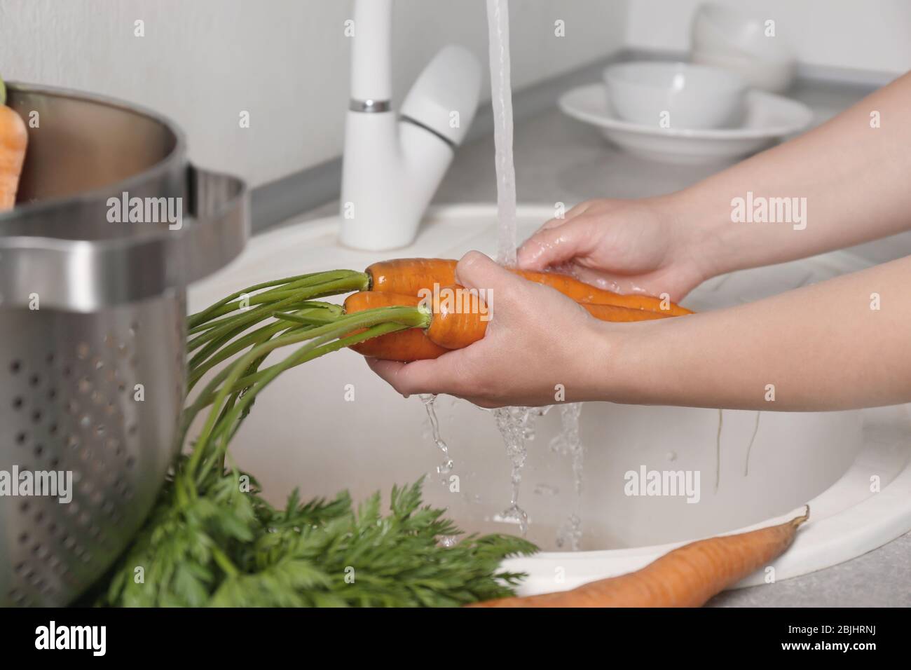 Woman washing fresh carrots in kitchen sink Stock Photo - Alamy