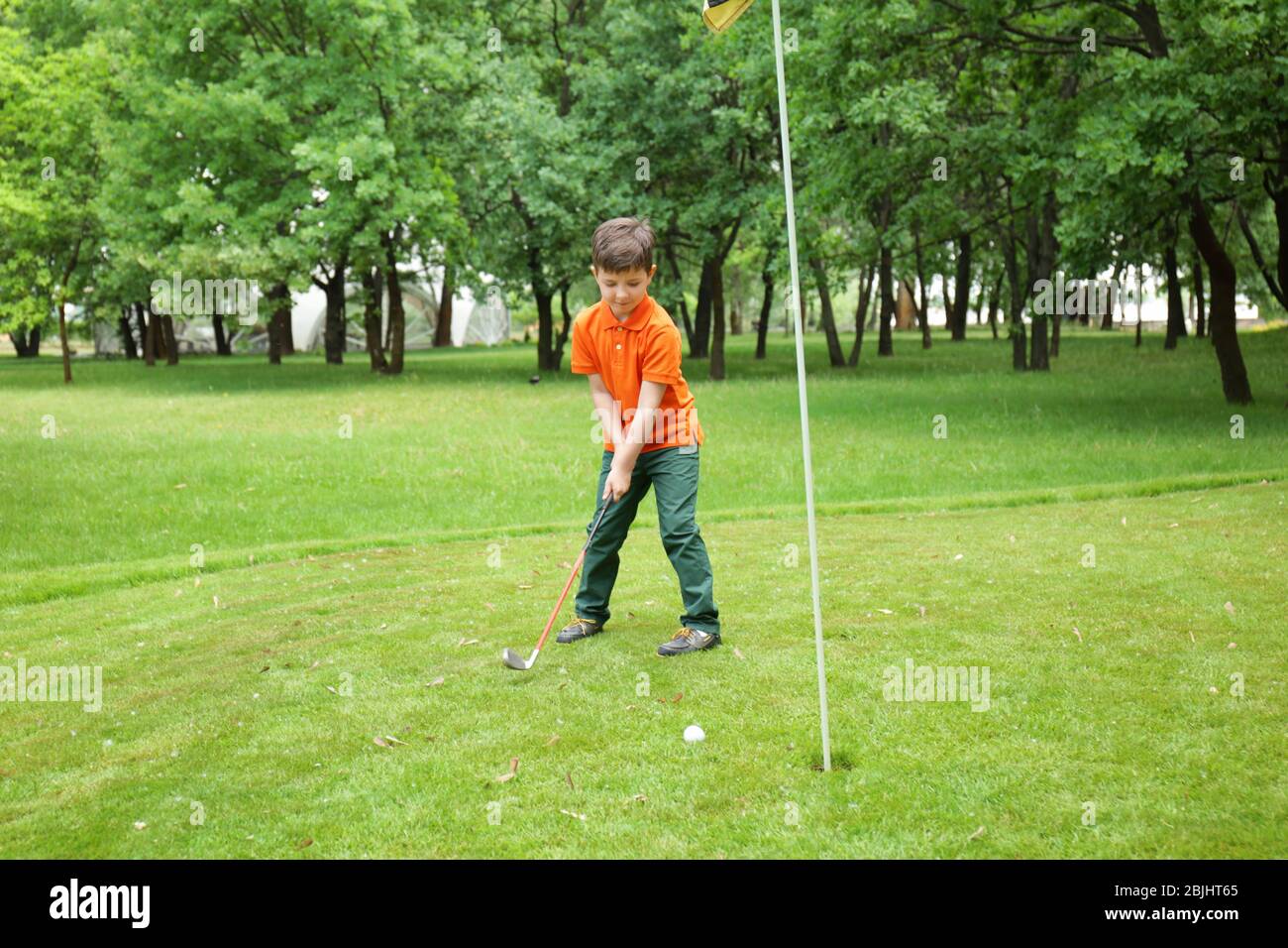 Cute boy playing golf on course in summer day Stock Photo - Alamy