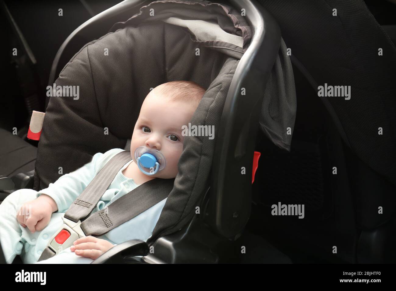 Cute baby boy with pacifier sitting in safety car seat Stock Photo - Alamy