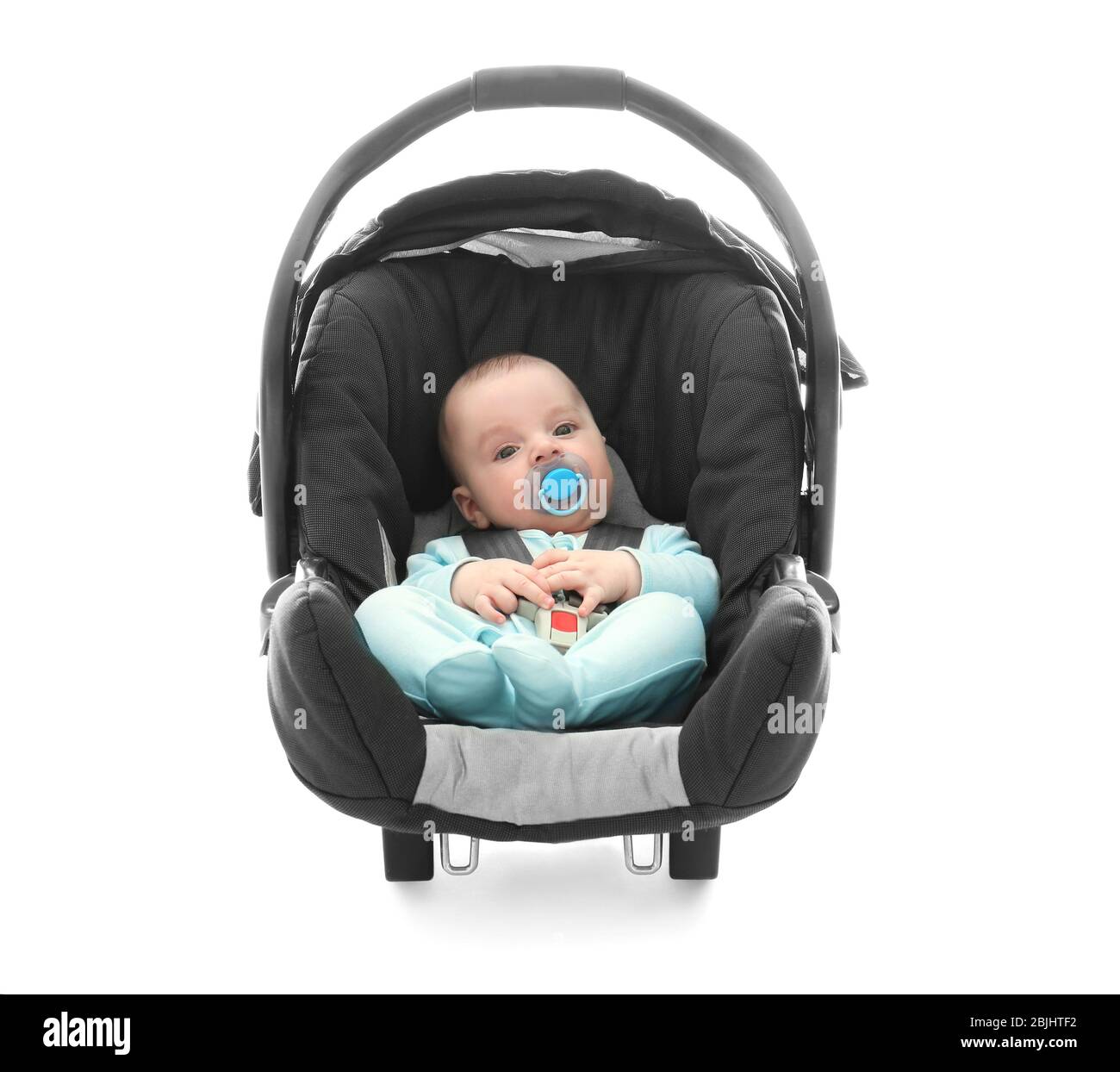 Adorable baby boy with pacifier sitting in car seat on white background ...